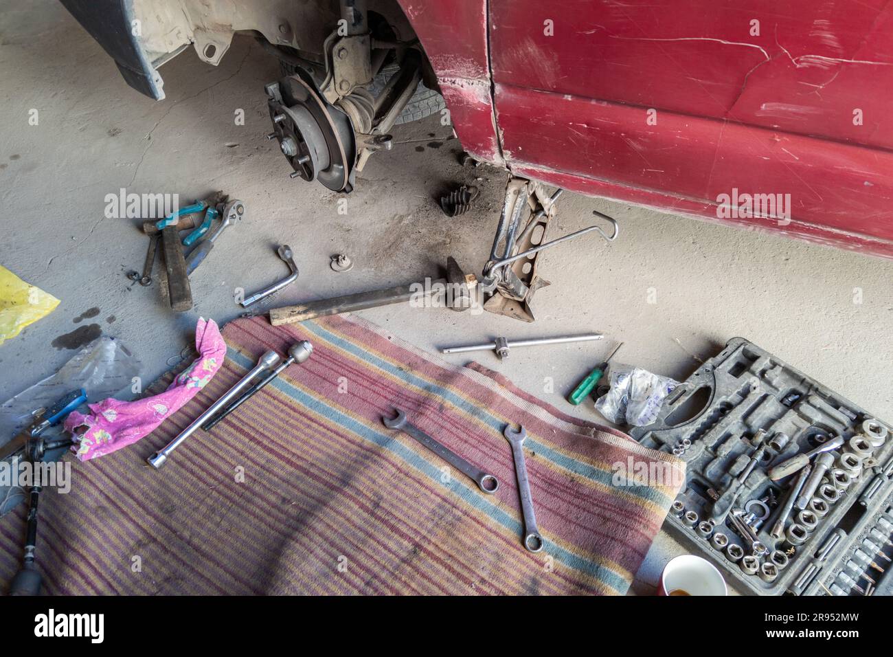 process of repair an old red car with old poor tools on concrete ...