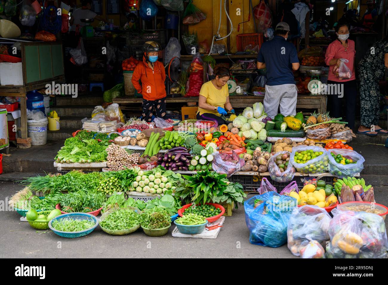 A female vendor tends to her makeshift stall woth fruit, vegetables and ...
