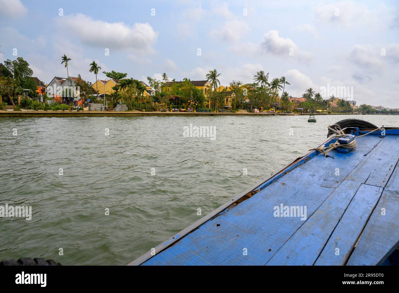 A blue wooden boat sails downstream on Thu Bon river on its way from ...