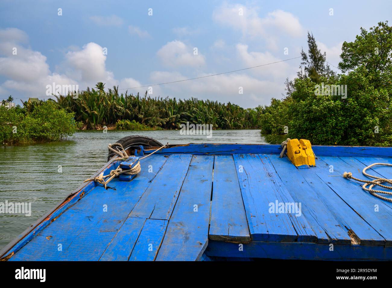 A blue wooden boat sails downstream on Thu Bon river on its way from ...