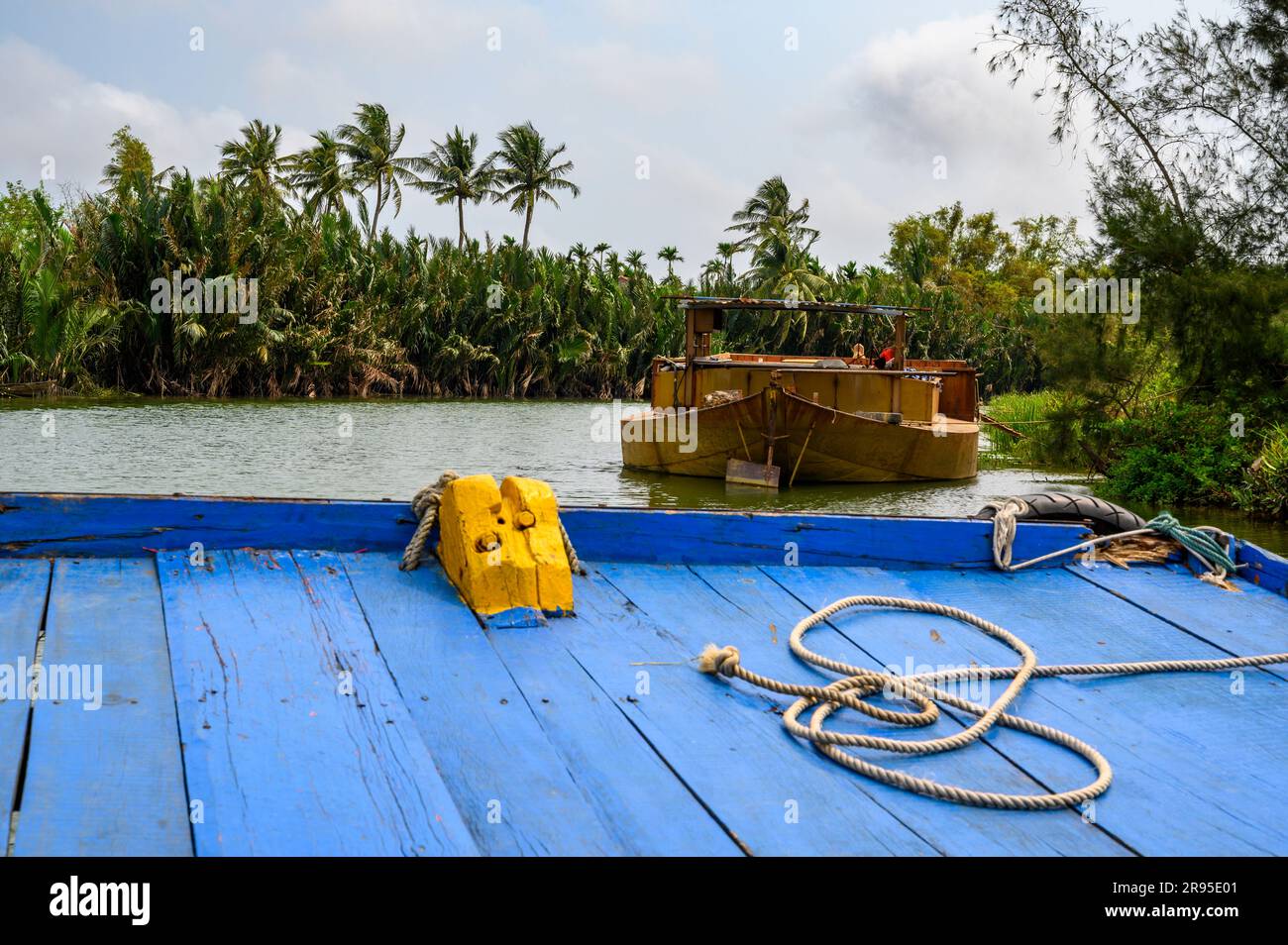 A blue wooden boat sails downstream on Thu Bon river on its way from ...