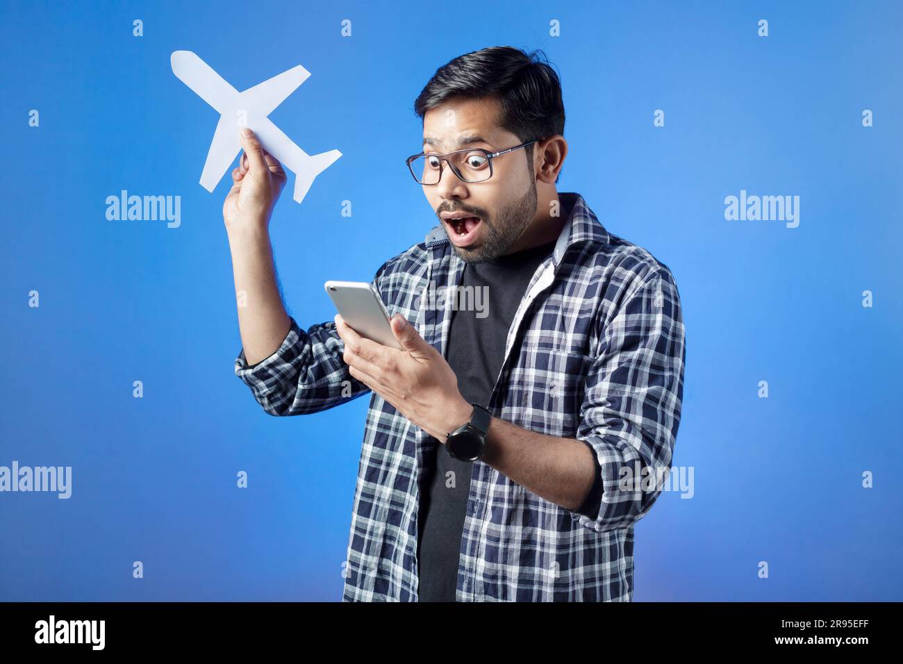 Surprised shocking man holding paper cutting airplane and looking at ...