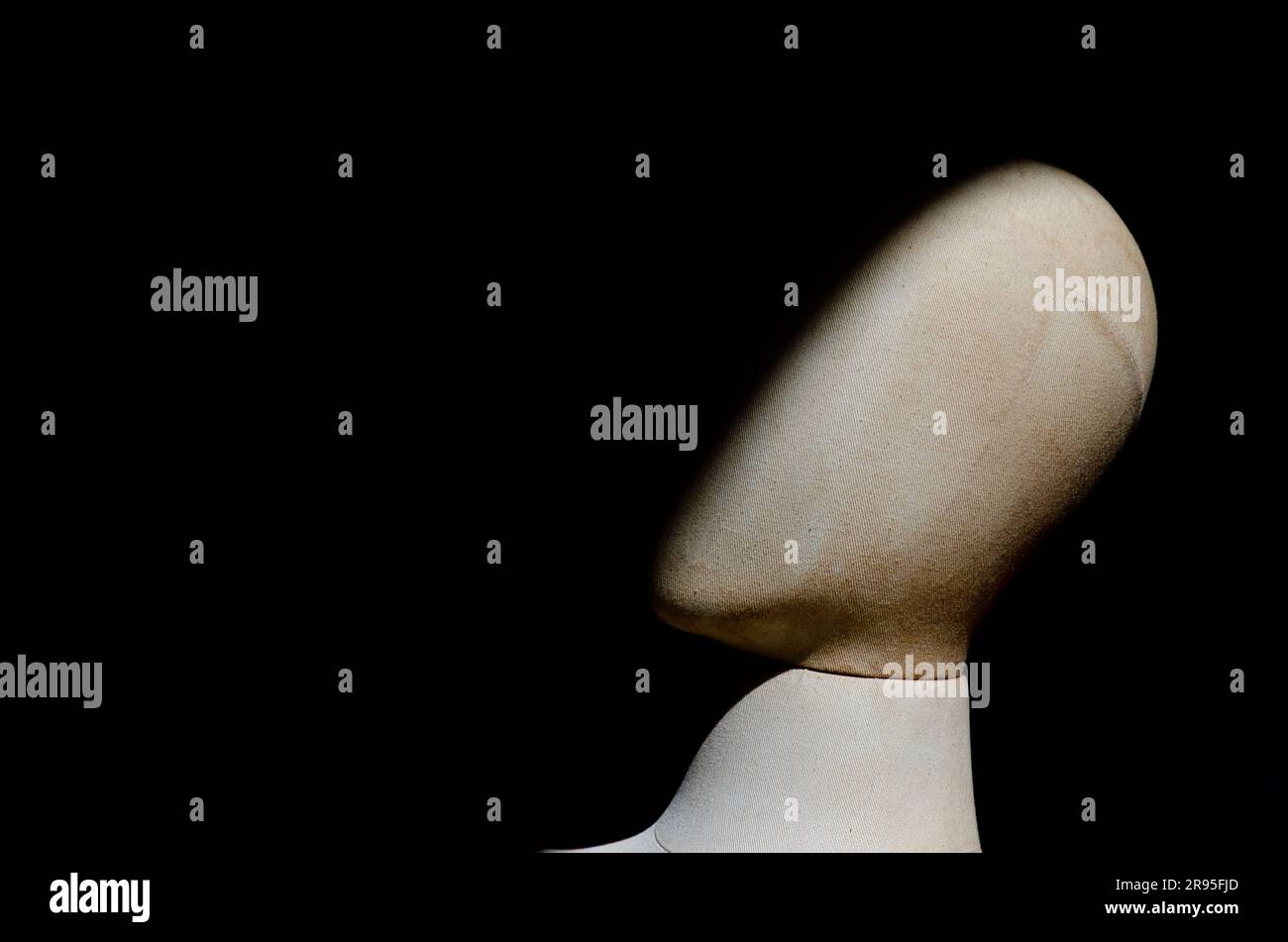 A wooden and plastic mannequin stands in the darkness with its head ...