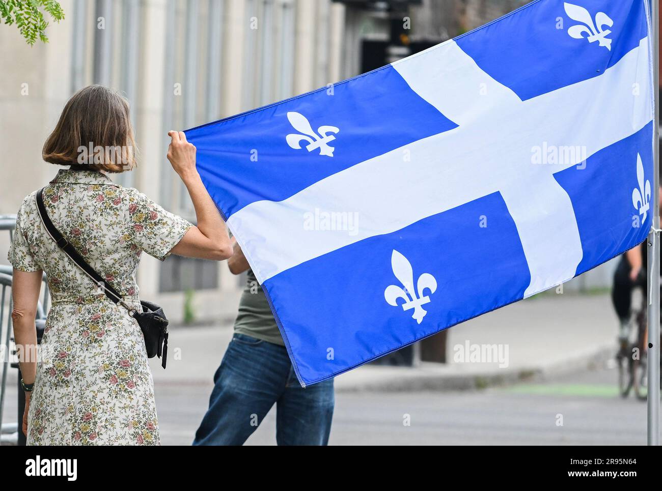 Montreal, Canada. 24th June, 2023. A woman poses next to a Quebec flag ...