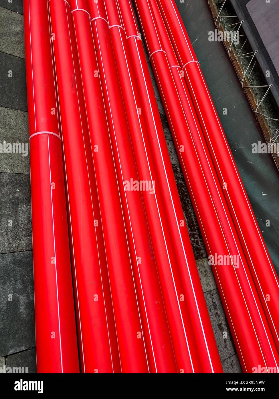 Red plastic pipes for communications stacked on the pavement Stock ...