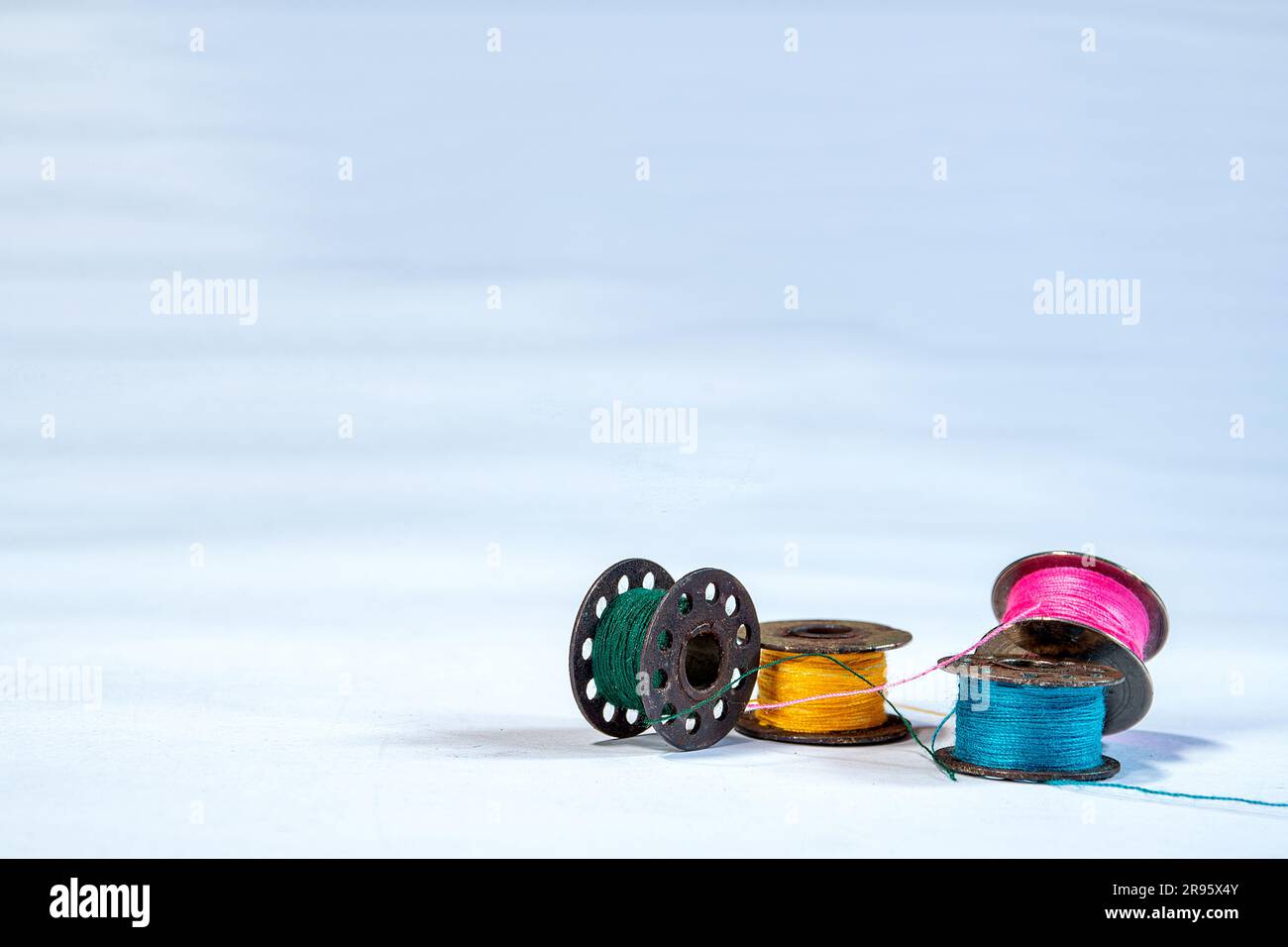 Various colored threads are wound on bobbins of a sewing machine ...