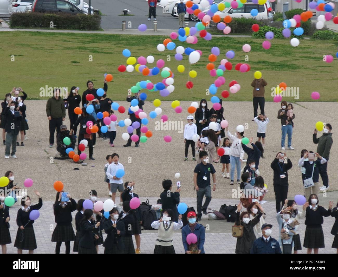 Balloons float into the sky as Japanese school children on the quayside ...