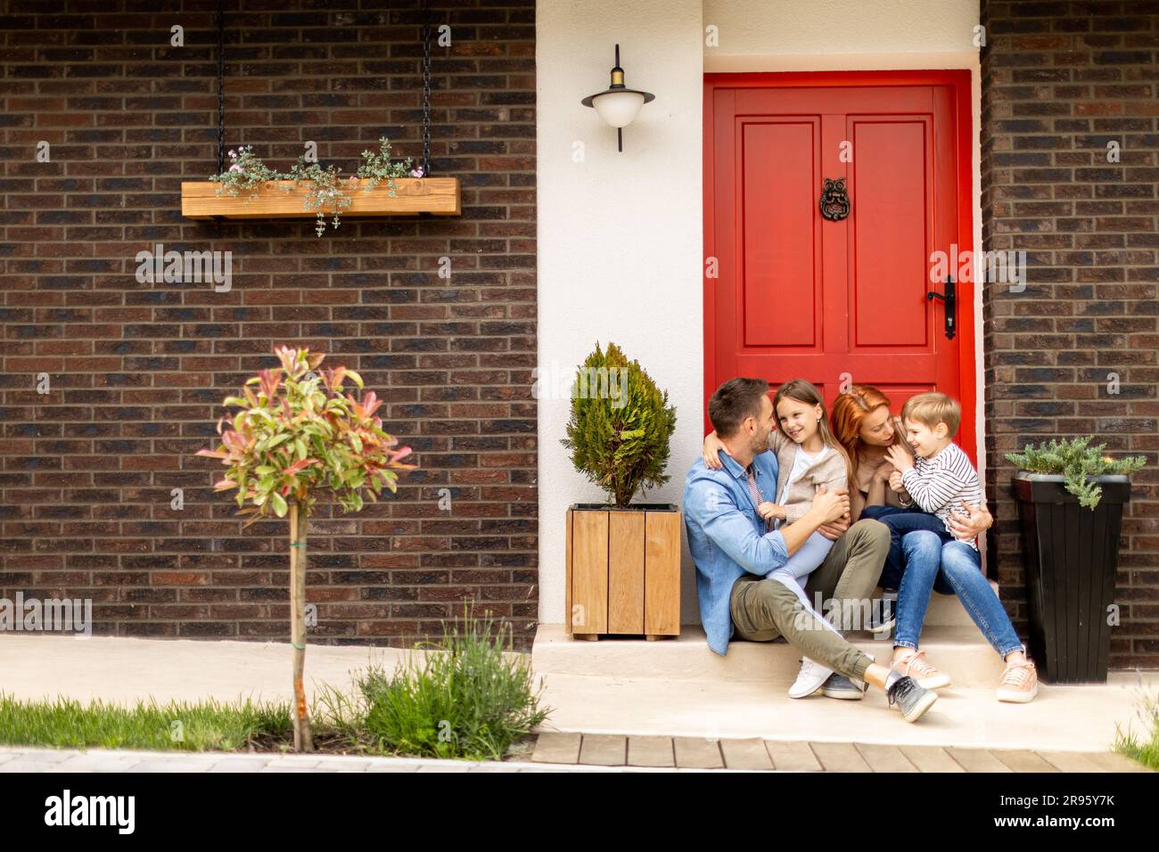 Family with a mother, father, son and daughter sitting outside on steps ...