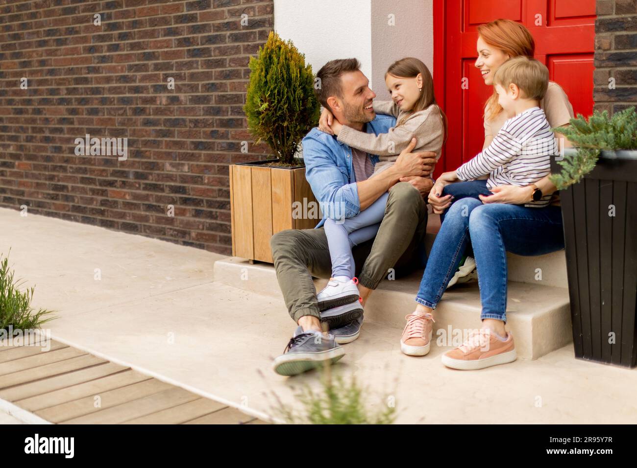 Family with a mother, father, son and daughter sitting outside on steps ...