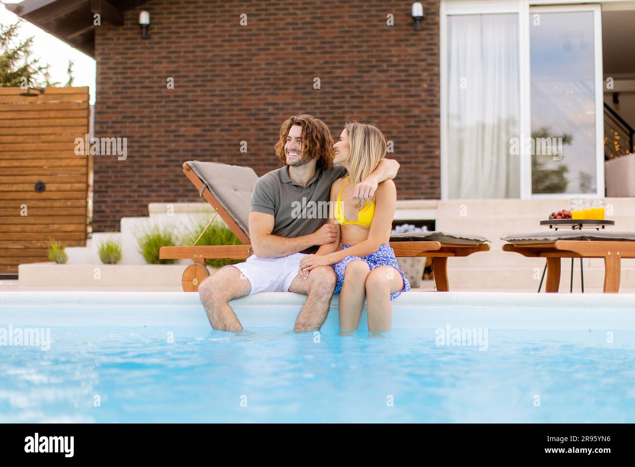 Handsome young couple relaxing by the swimming pool in the house backyard Stock Photo - Alamy