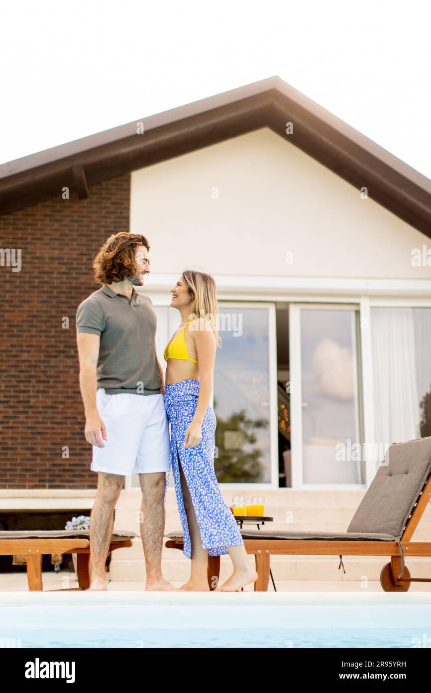 Handsome young couple relaxing by the swimming pool in the house ...