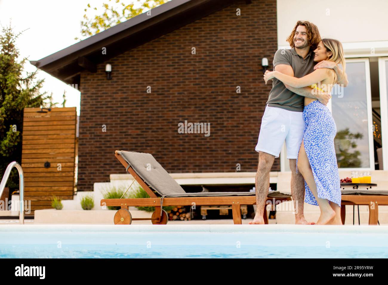 Handsome young couple relaxing by the swimming pool in the house backyard Stock Photo - Alamy