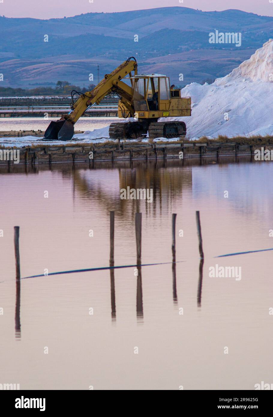 Salt farm excavator with sunset and a salt mountain Stock Photo - Alamy