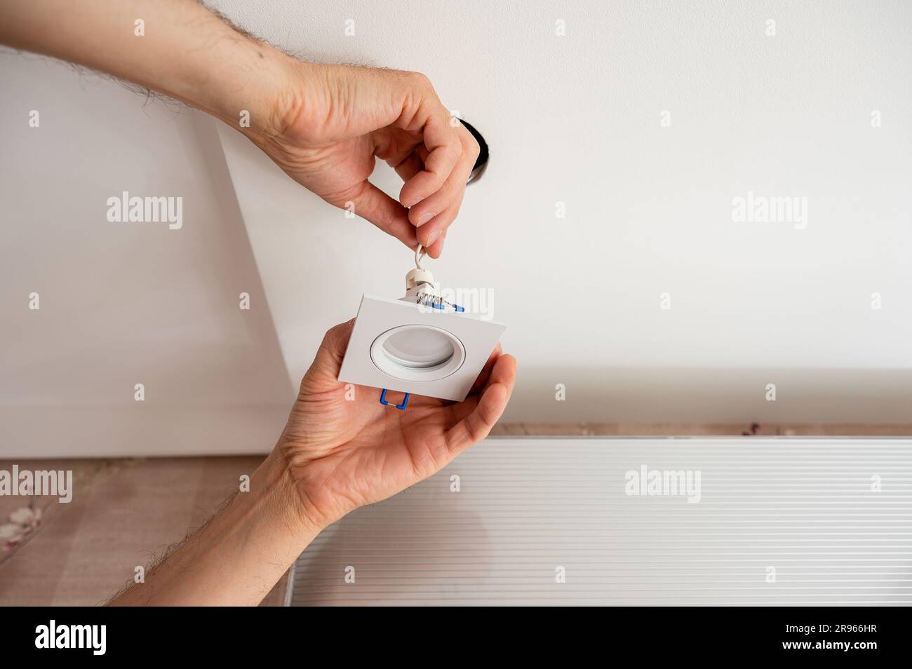 Installation of point light, hand inserts the lamp into the ceiling ...