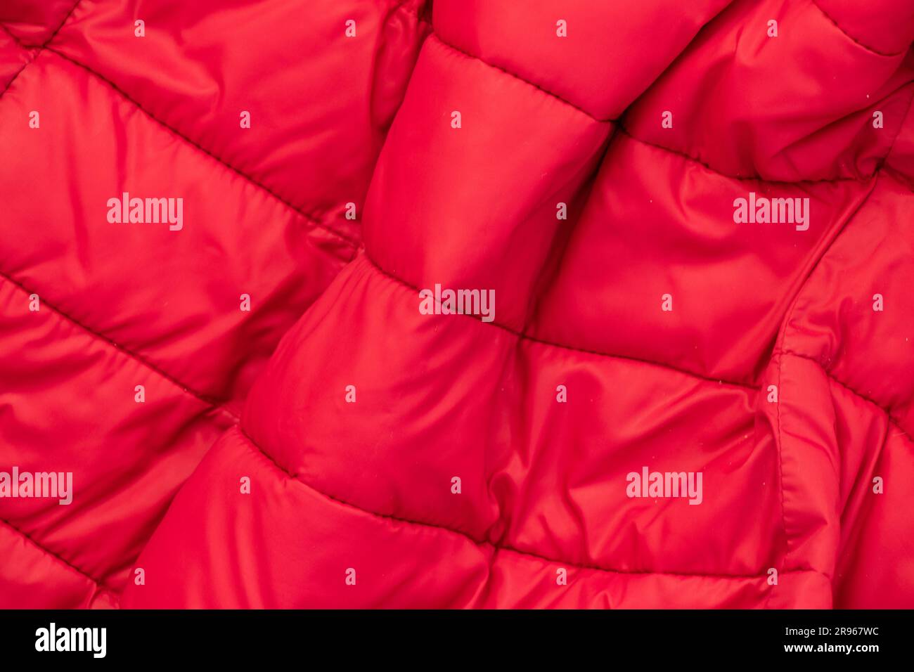 red fabric of a warm puffed jacket as a background close up Stock Photo ...