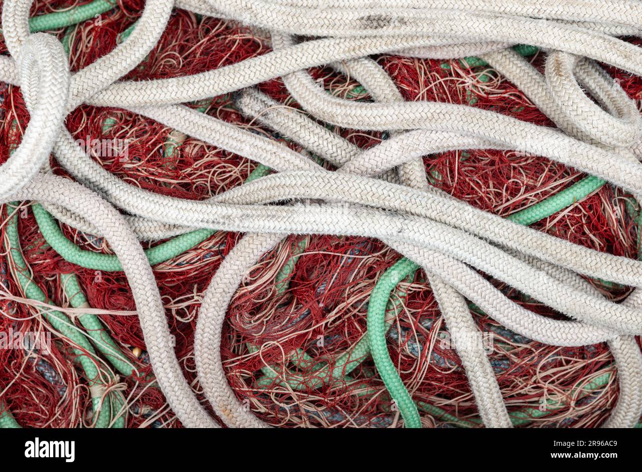 White and green marine rope and tangled red fishing net close-up in ...