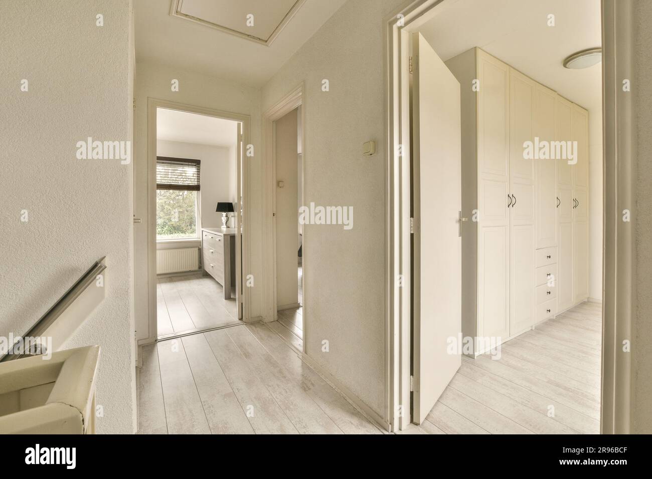 a hallway with white walls and wood flooring on the left side of the ...