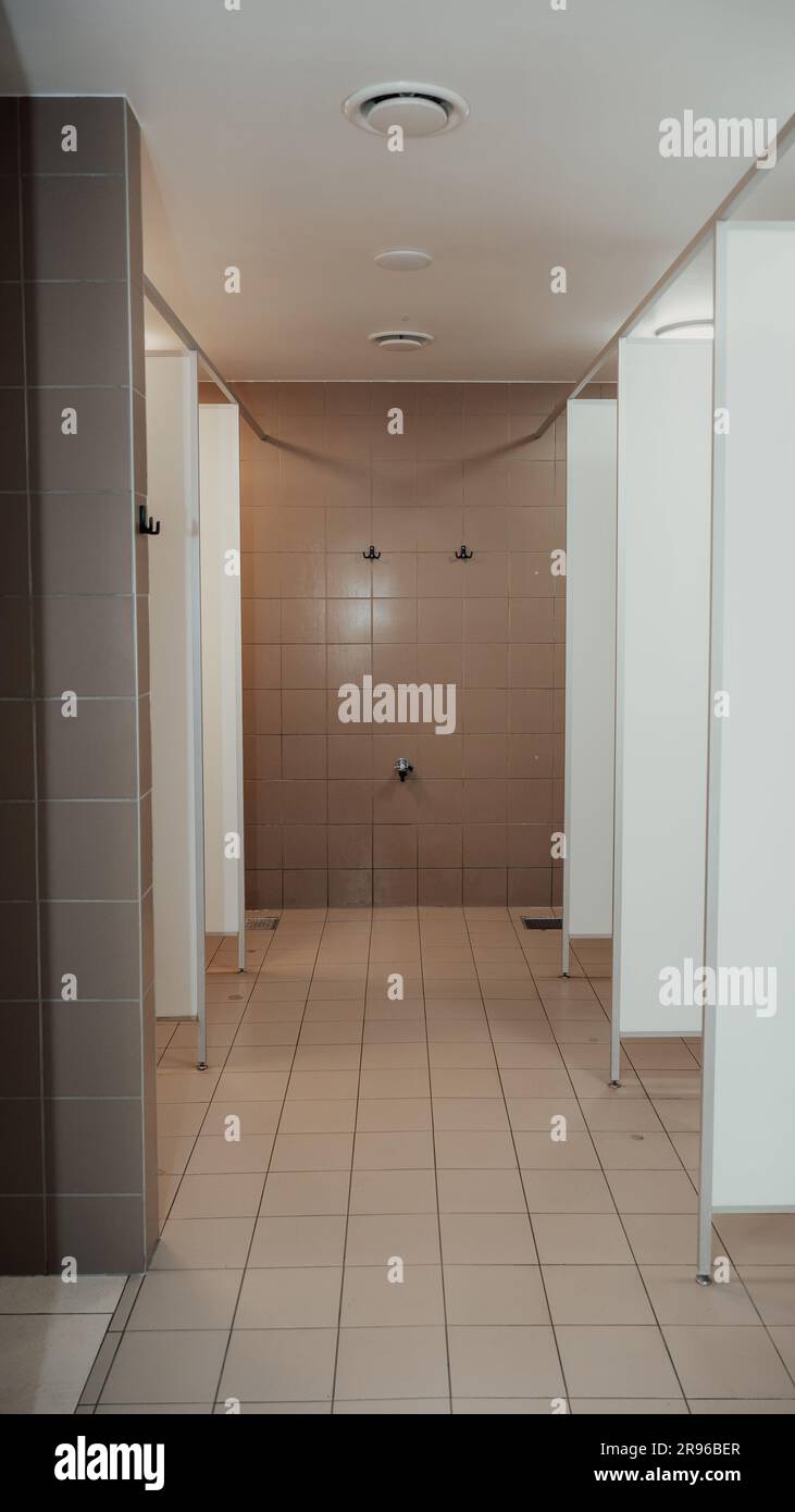 A pristine public restroom with glossy tiled walls and floor, featuring ...