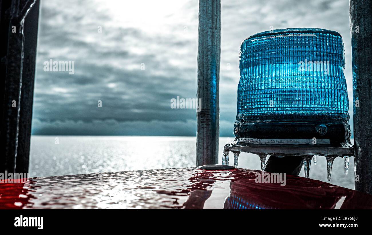 A blue strobe light sits atop a metal surface in a rainy outdoor ...