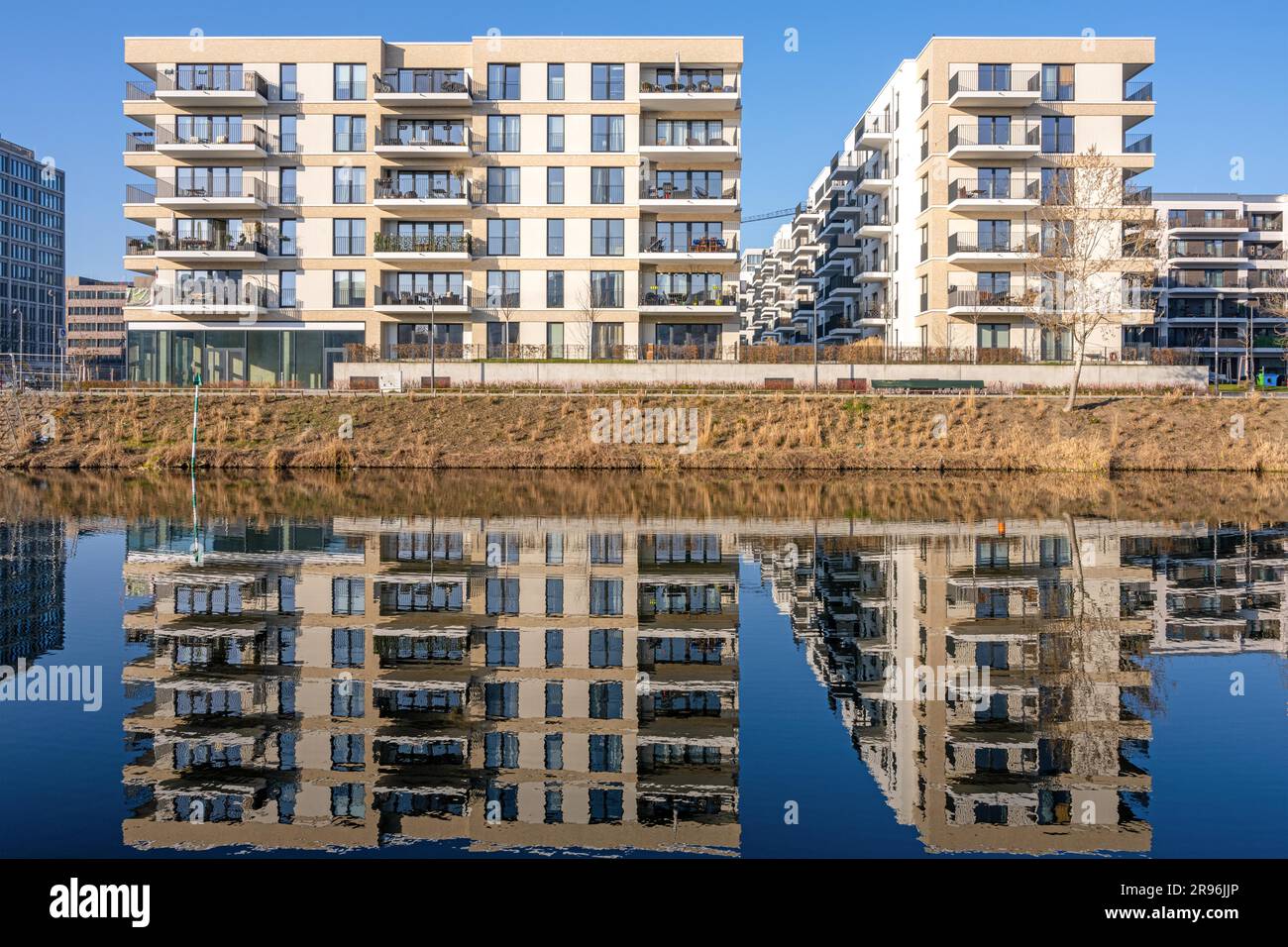 New residential buildings reflected in a canal, seen in Berlin, Germany ...