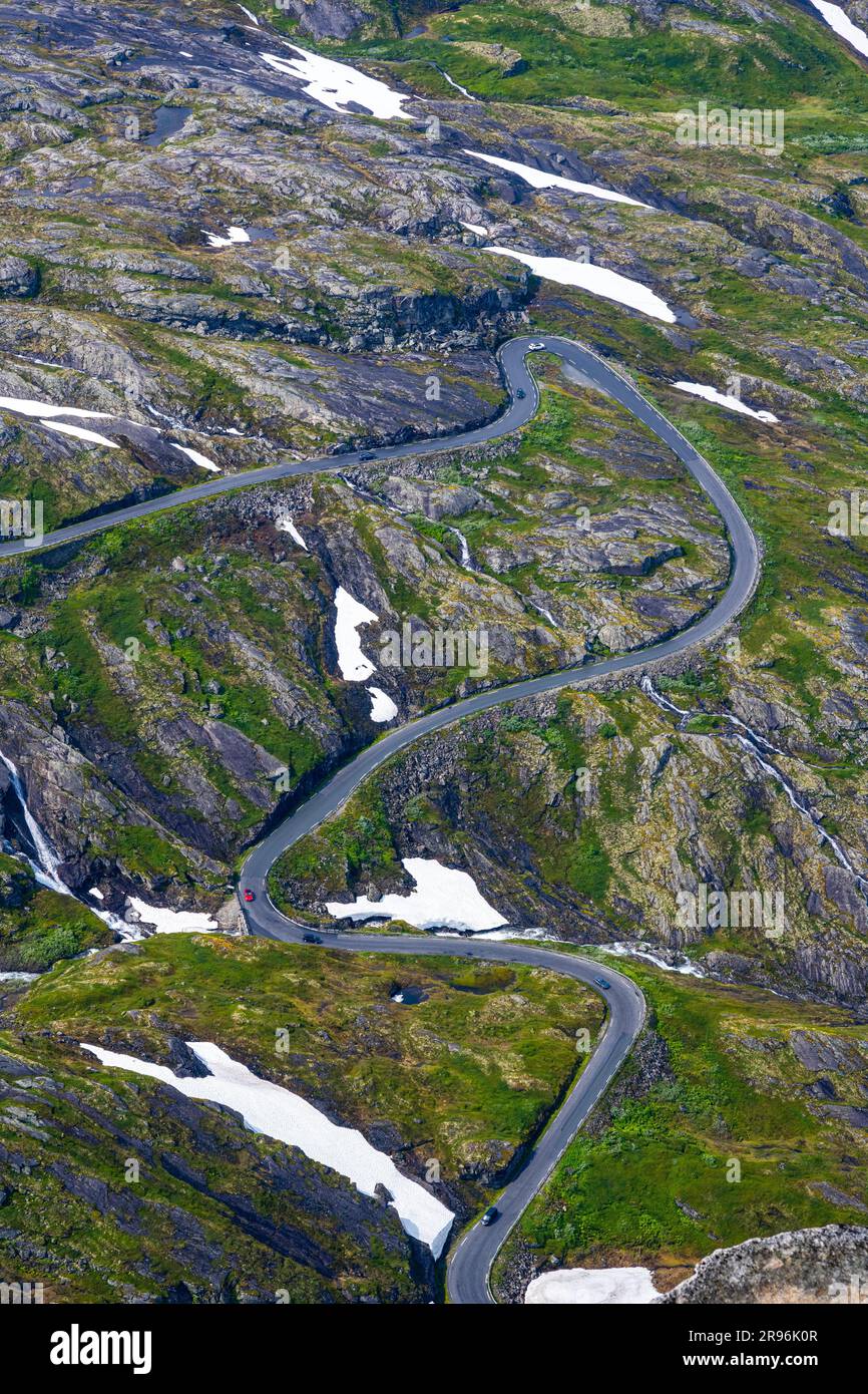 Green landscape with patches of snow and a winding road, seen in Norway ...