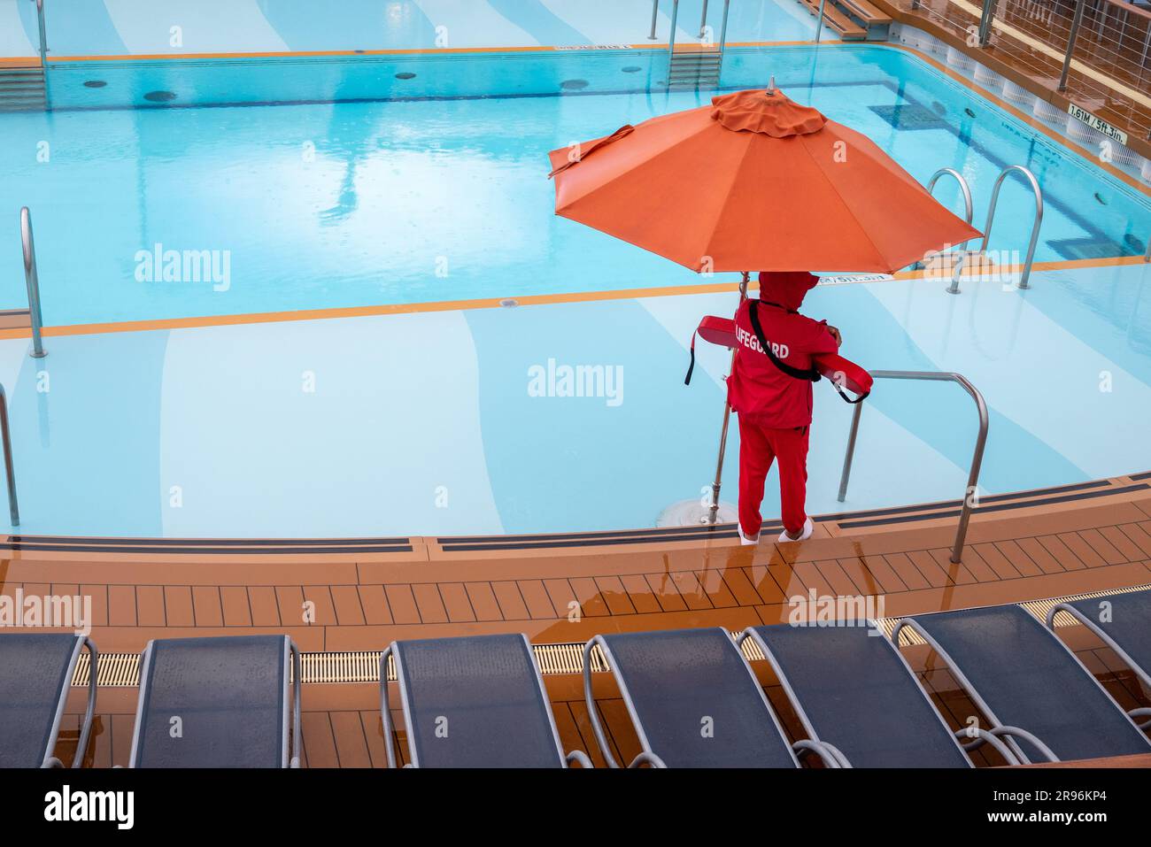 Lifeguard standing in front of an empty swimming pool on a rainy day ...
