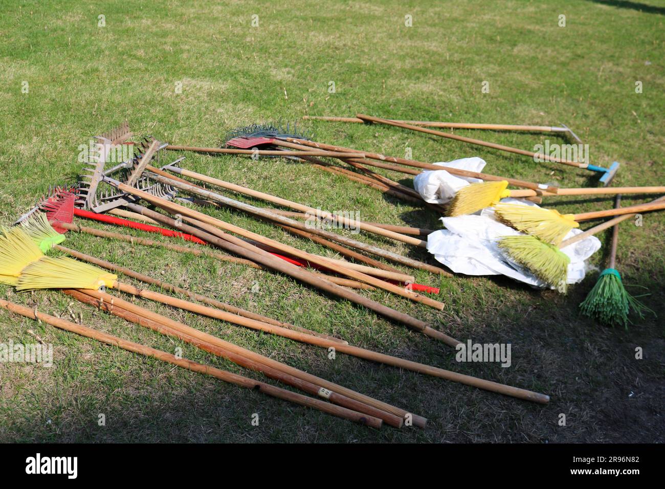 Many rakes, shovels and cleaning brushes lie on the green grass Stock ...