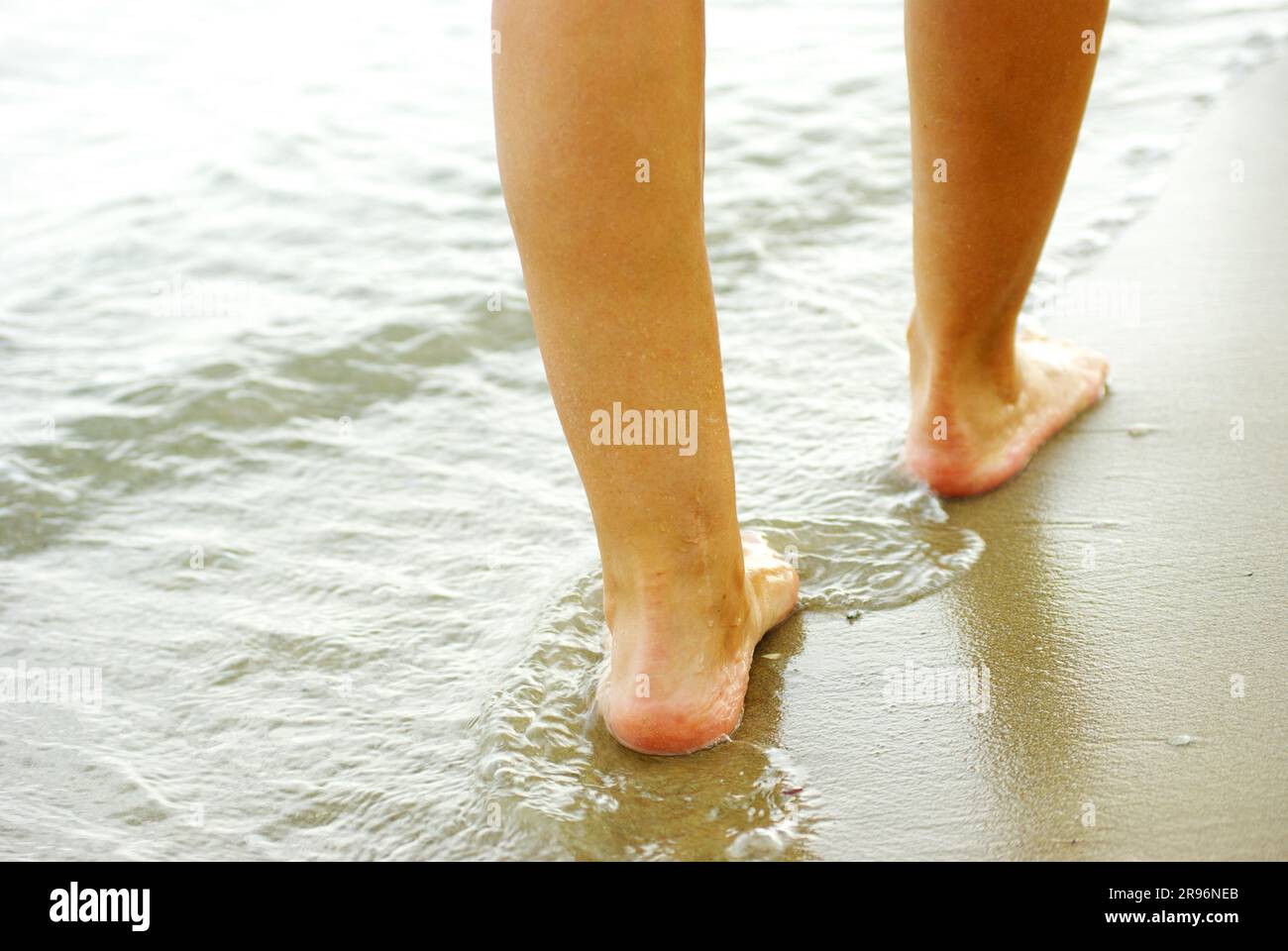 Feet in the water on the beach Stock Photo - Alamy