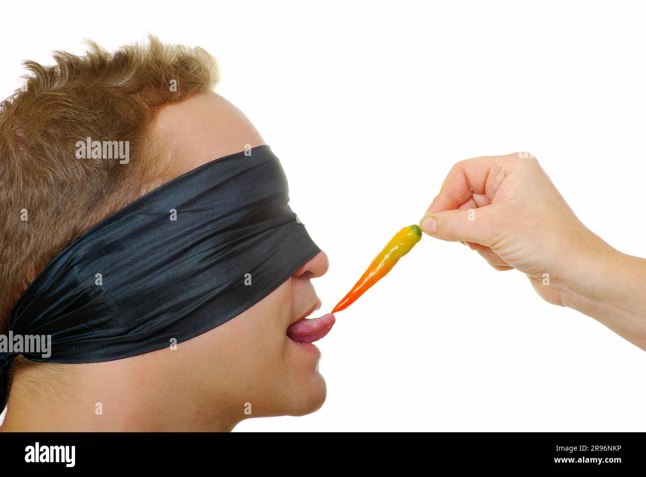 Man with bandaged eyes tasting Hot Chili (Capsicum annuum), side, Hot ...