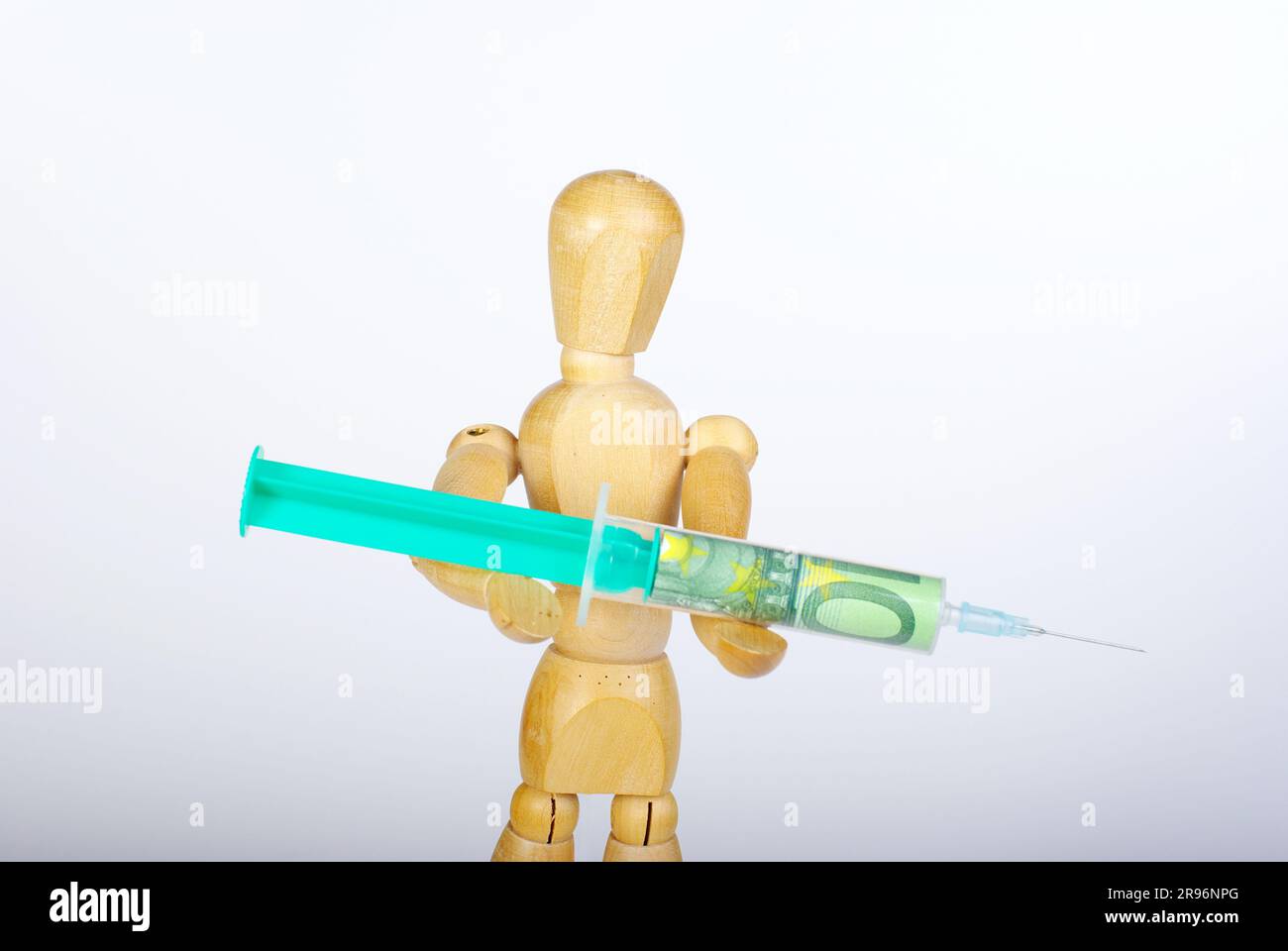 Wooden figure holding syringe with euro note, financial injection ...