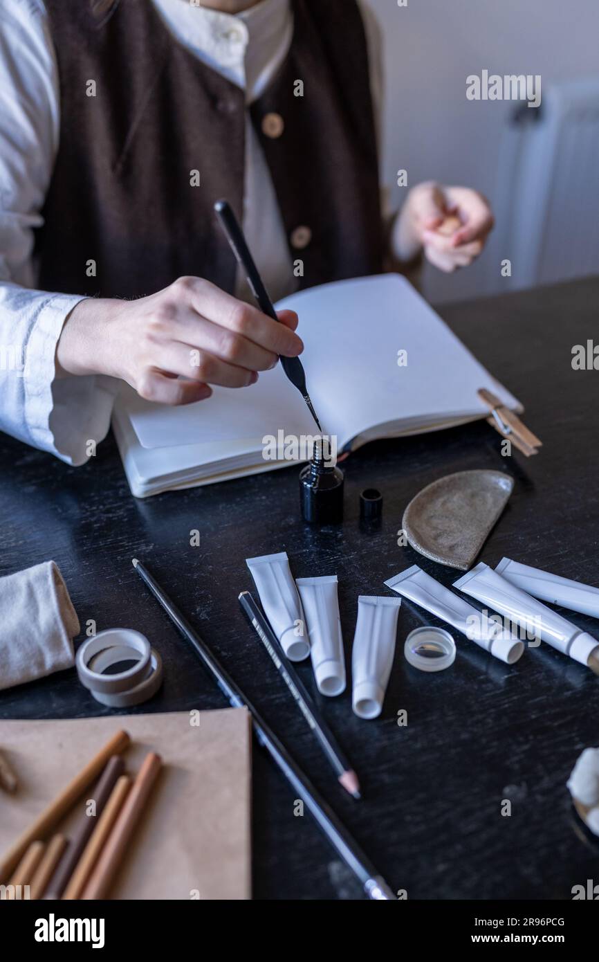 Female artist painting with ink in sketchbook Stock Photo - Alamy