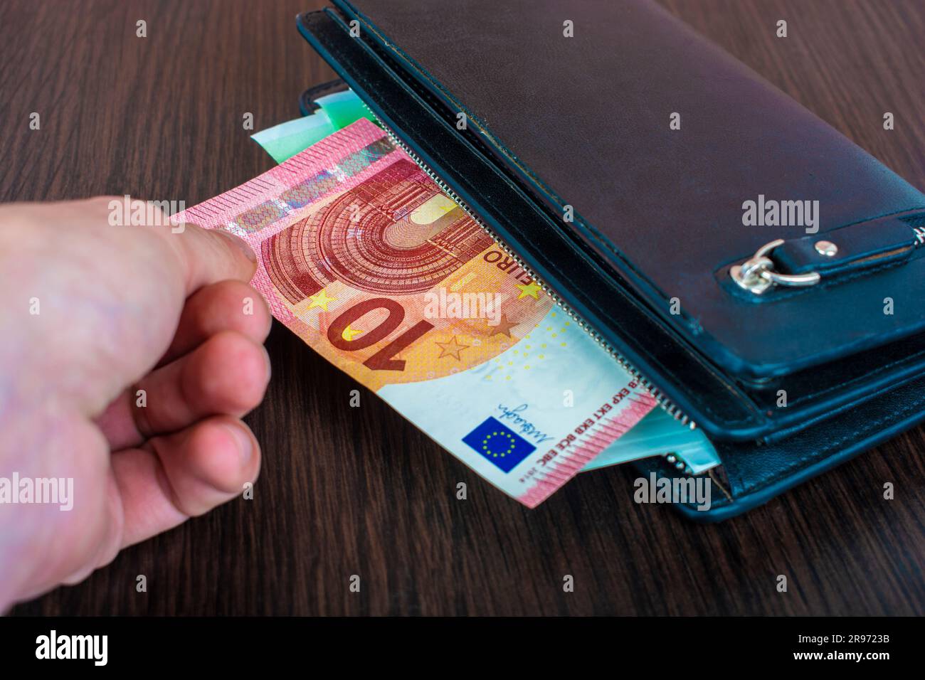 The man's hand pulls out bills with a leather purse and the withdrawal ...