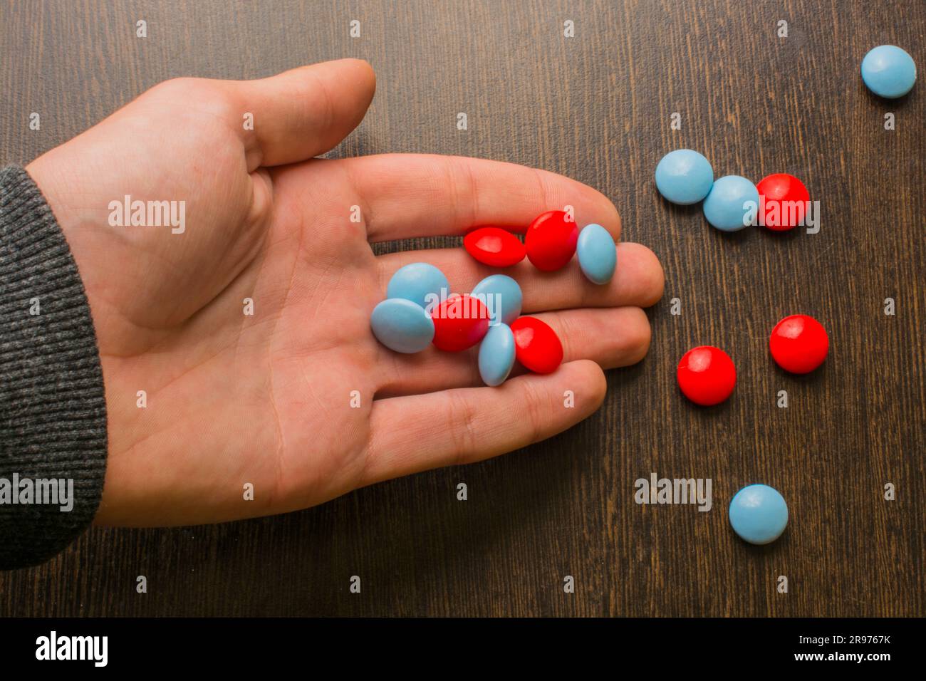 red and blue tablets in hand on the background of a wooden table Stock ...