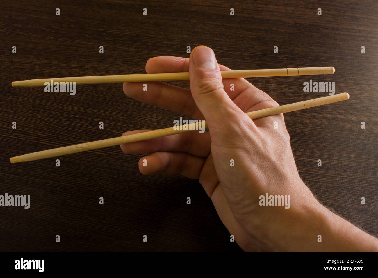 chopsticks in the right hand on a background of brown wood Stock Photo ...