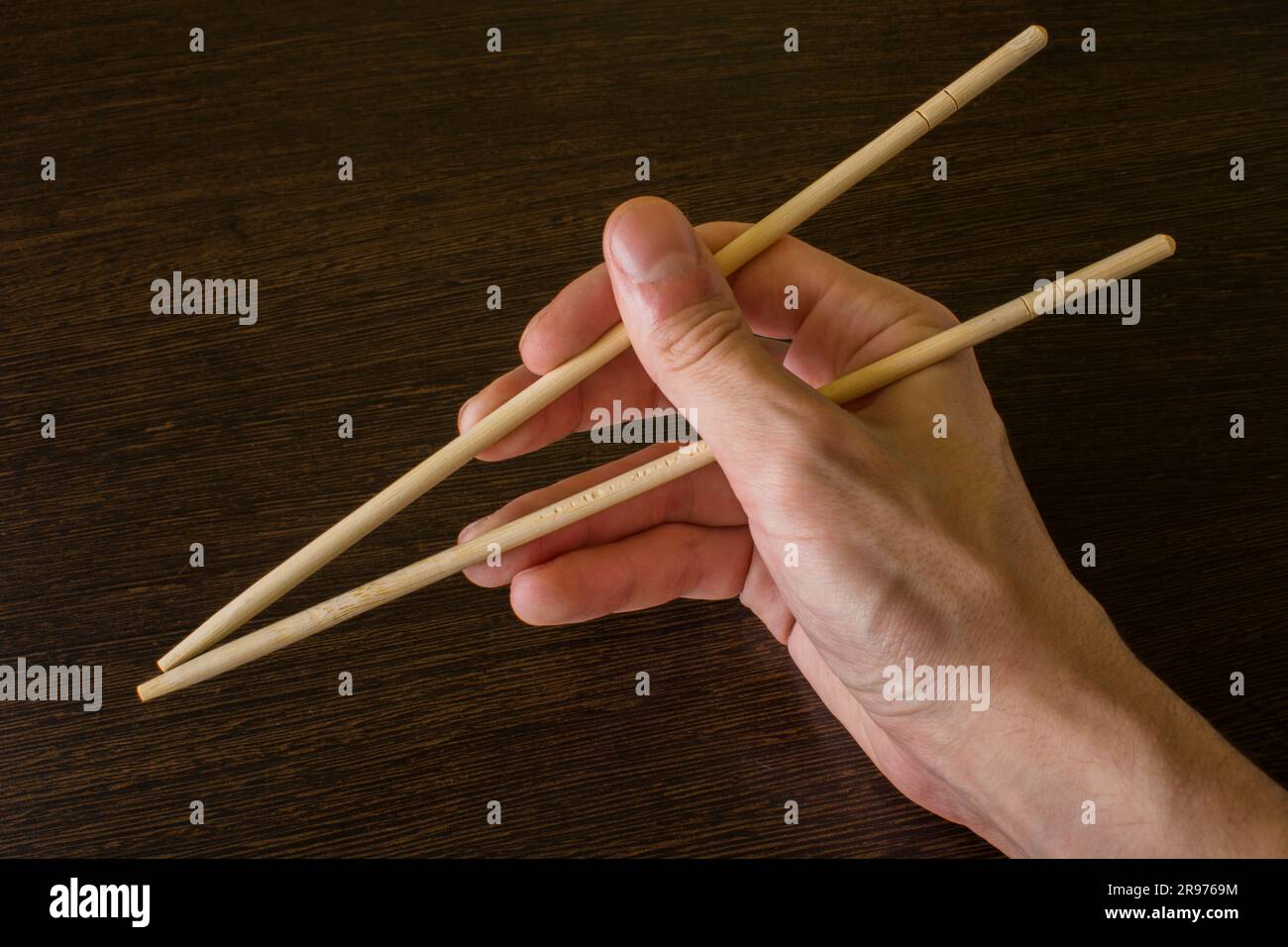 chopsticks in the right hand on a background of brown wood Stock Photo ...