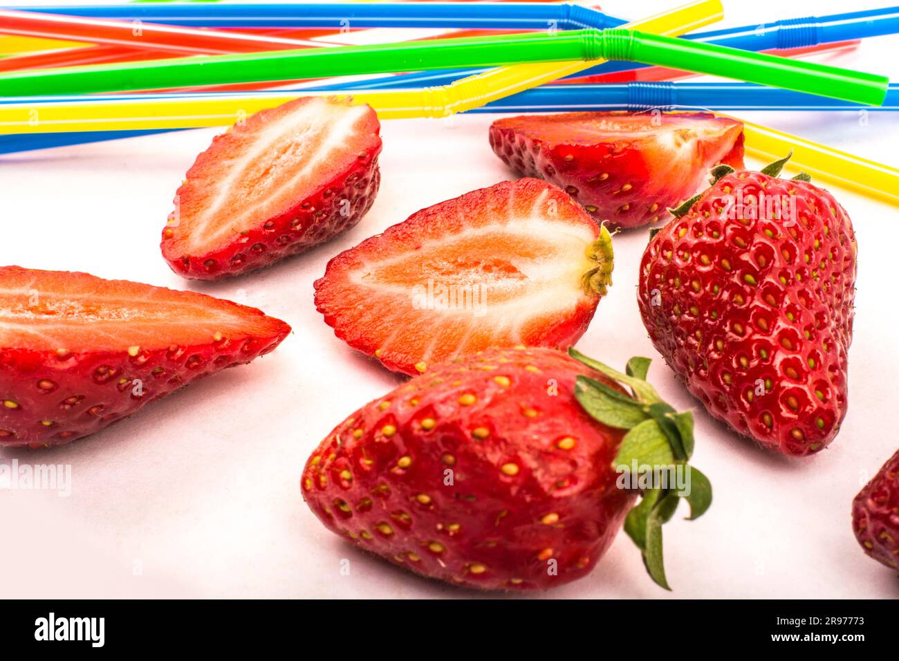 Strawberry and colored straws scattered on a white background Stock ...