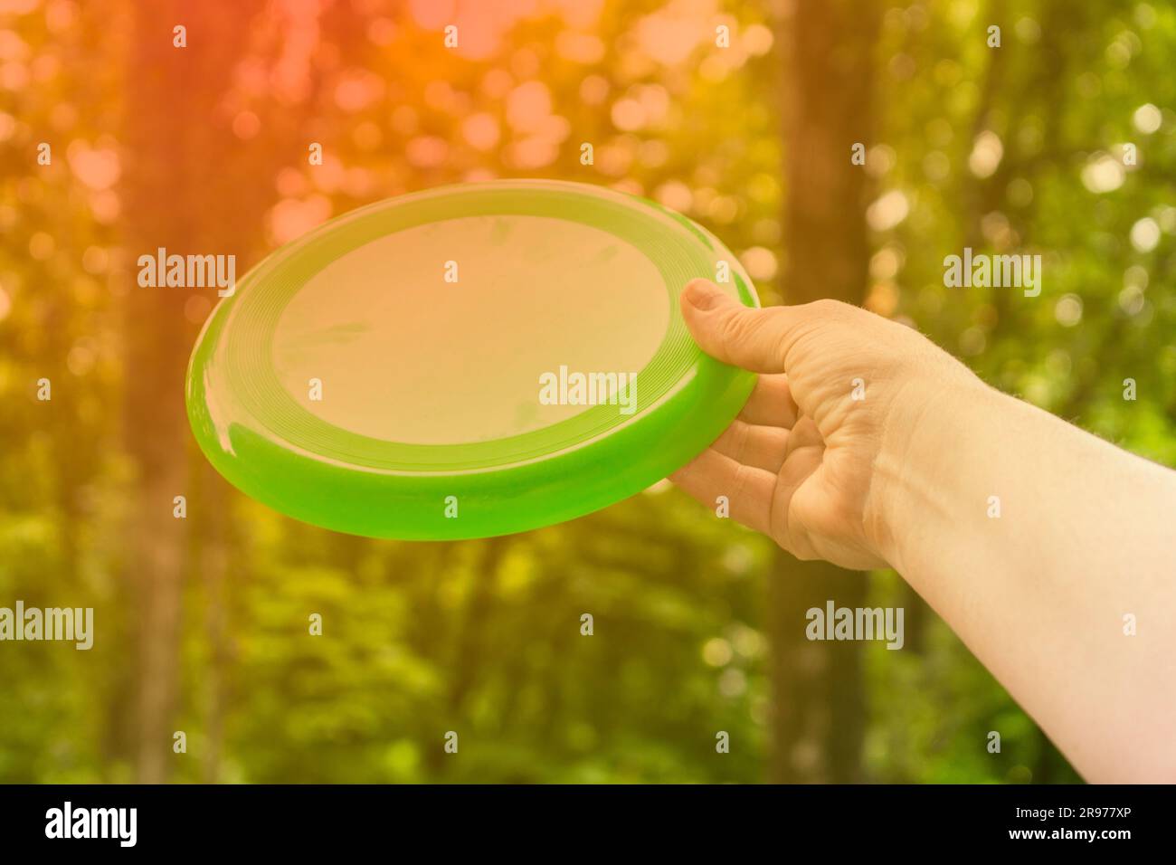 hand throwing a frisbee disc in the park on a summer day with a flash ...