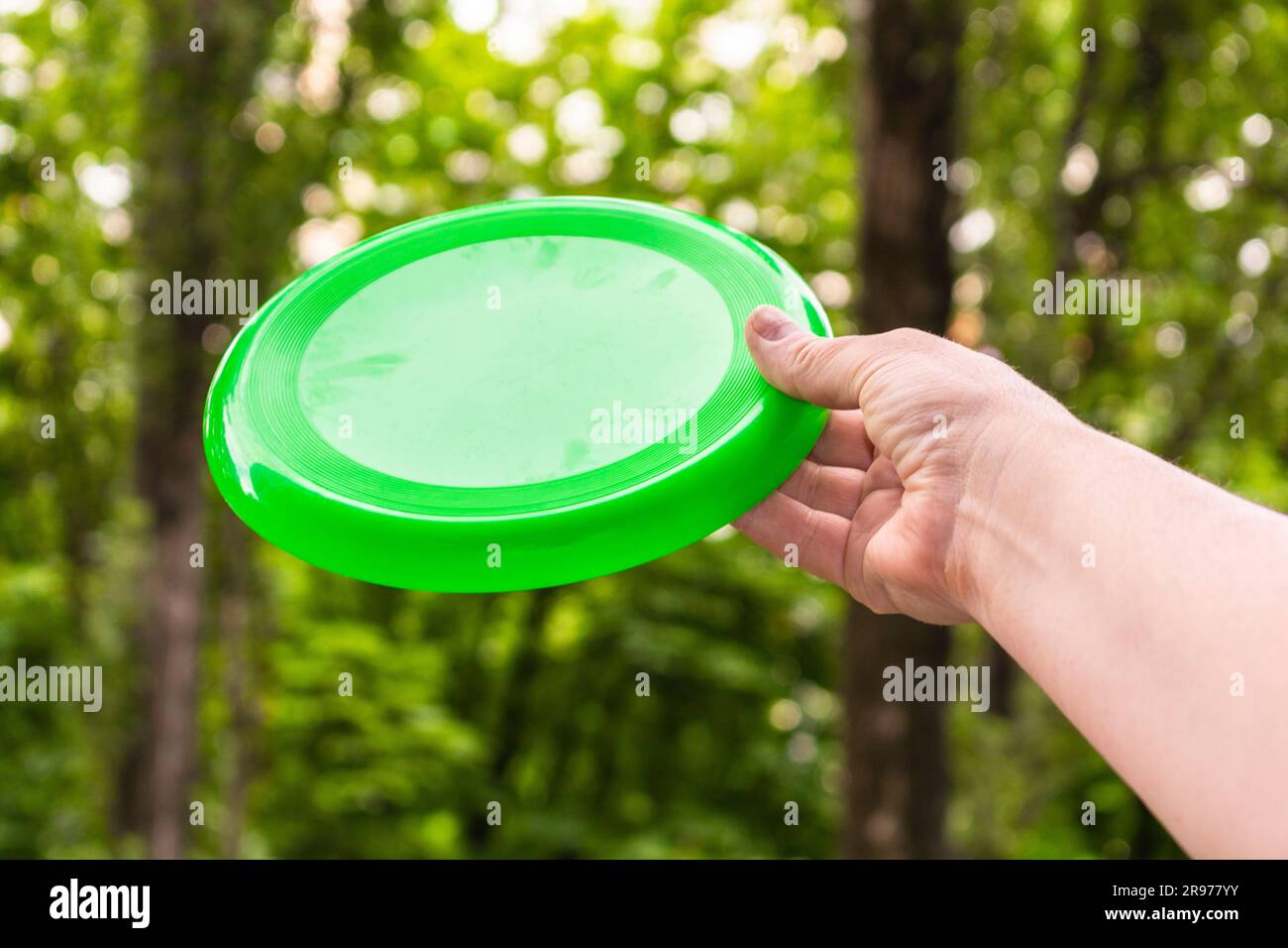 hand throwing a green frisbee disc in the park on a summer day Stock ...
