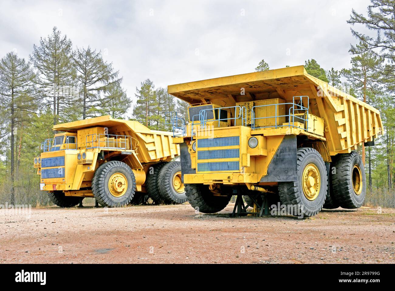 two yellow mining dump trucks stand on legs in the forest Stock Photo ...