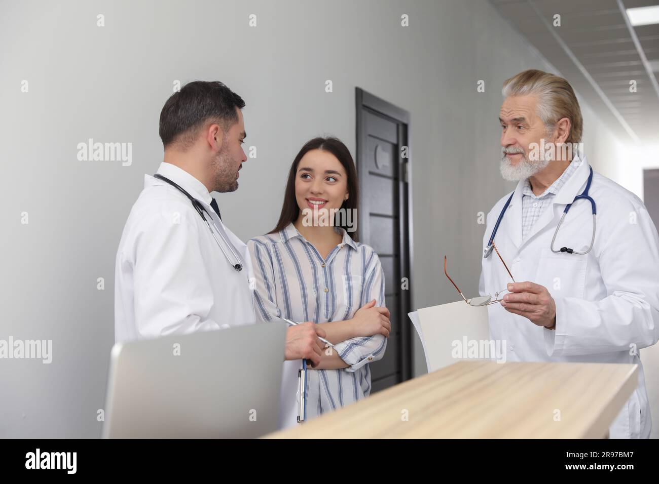 Doctors consulting patient near reception desk in clinic hall Stock ...
