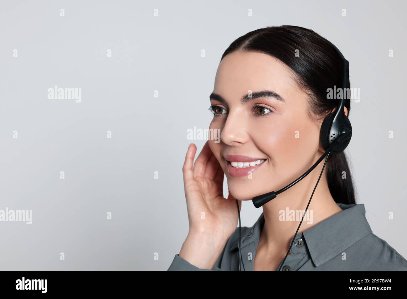 Hotline operator with modern headset on light grey background, space ...