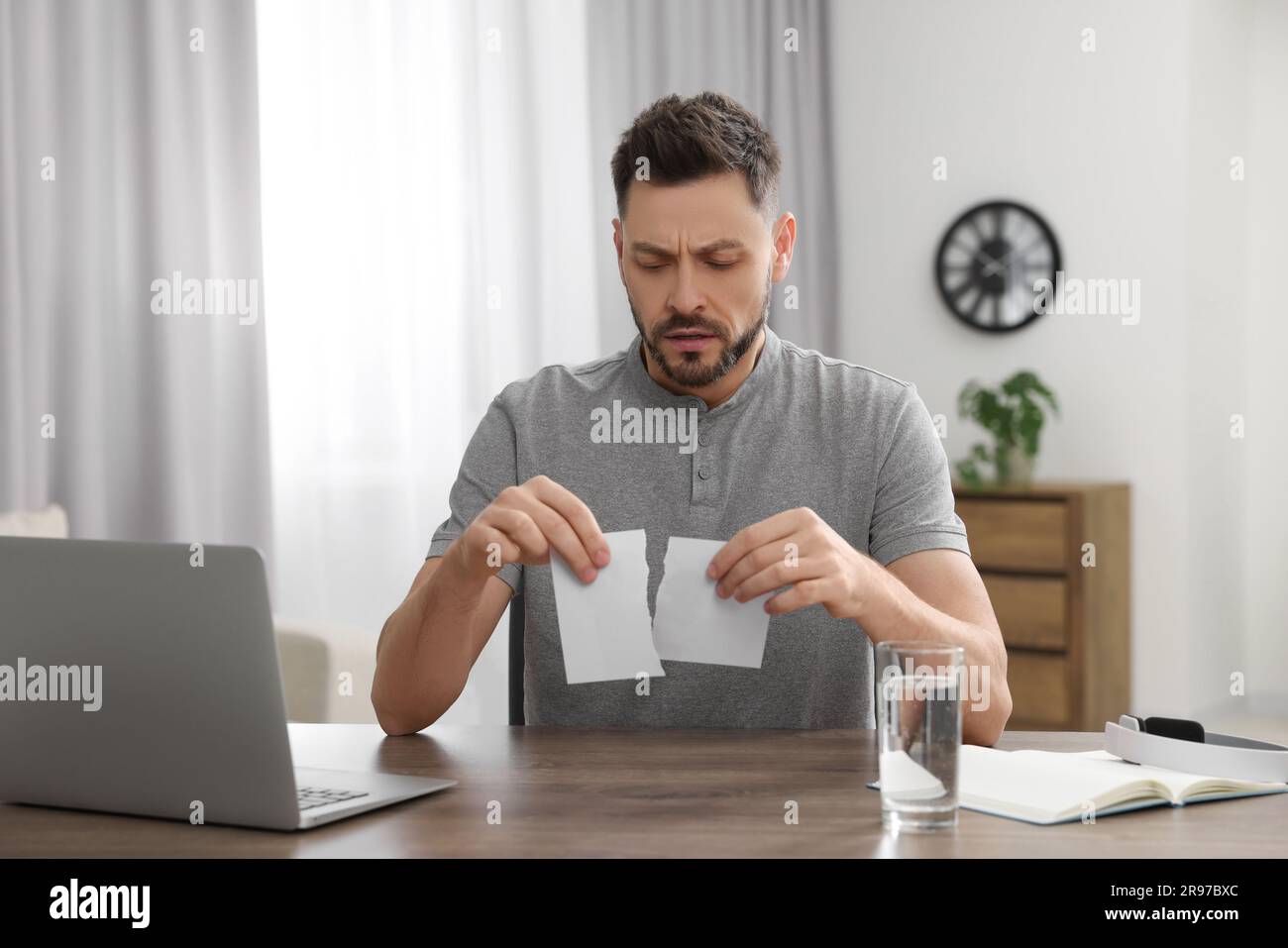 Man ripping photo at table indoors. Divorce concept Stock Photo - Alamy
