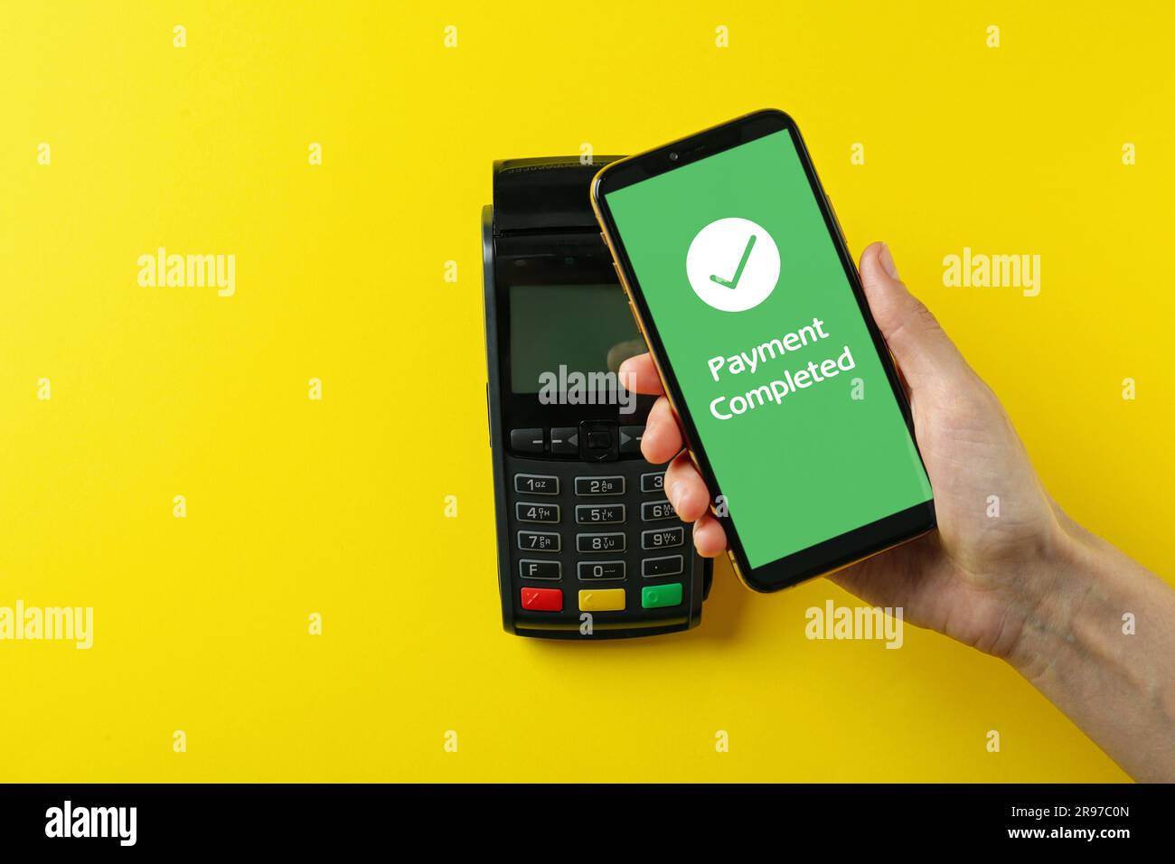 Woman using terminal for contactless payment with smartphone on yellow ...