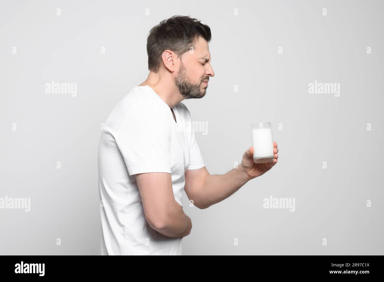 Man with glass of milk suffering from lactose intolerance on white ...