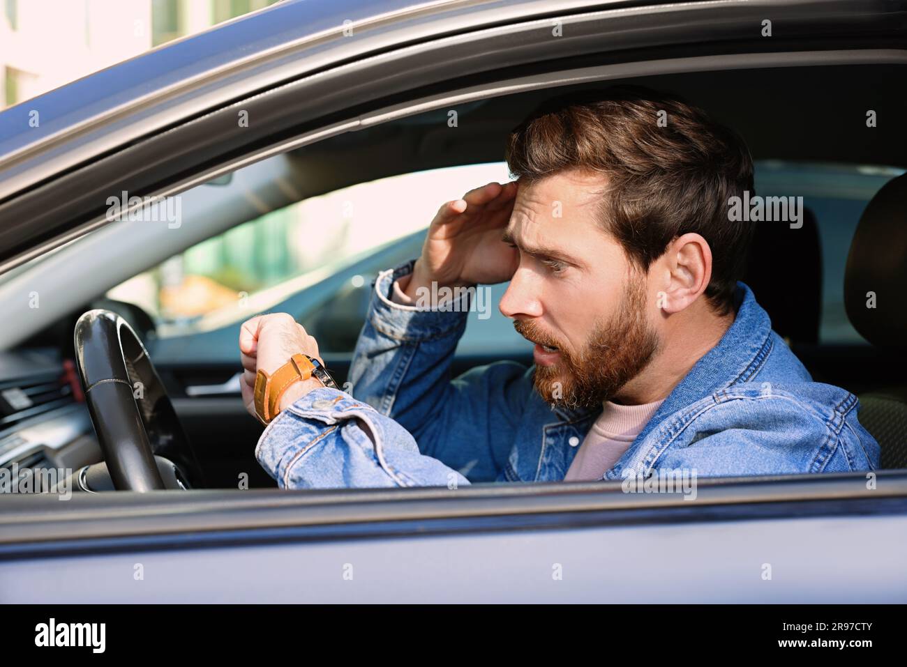 Emotional man checking time on watch in car. Being late concept Stock ...