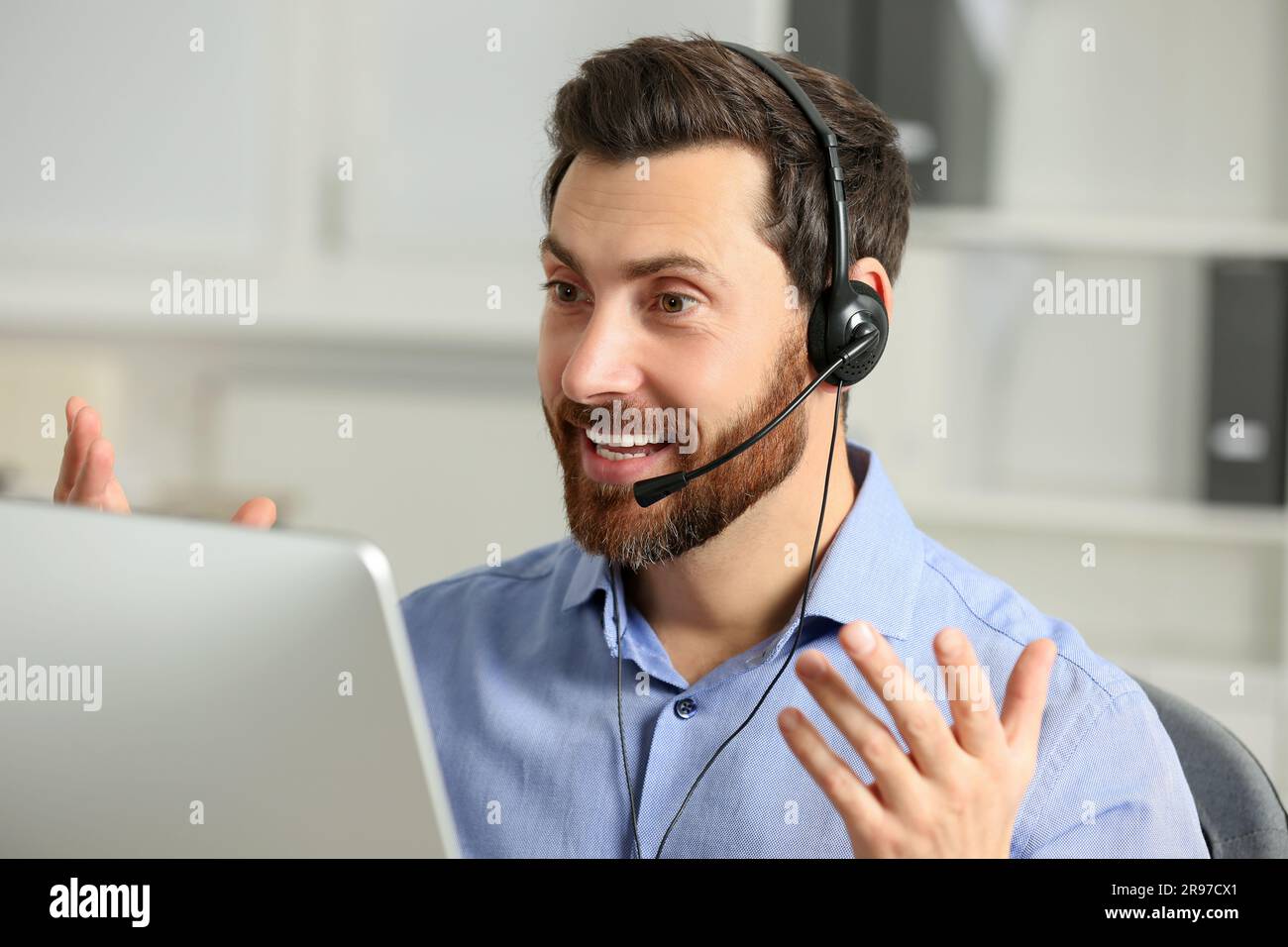 Emotional hotline operator with headset working in office Stock Photo ...