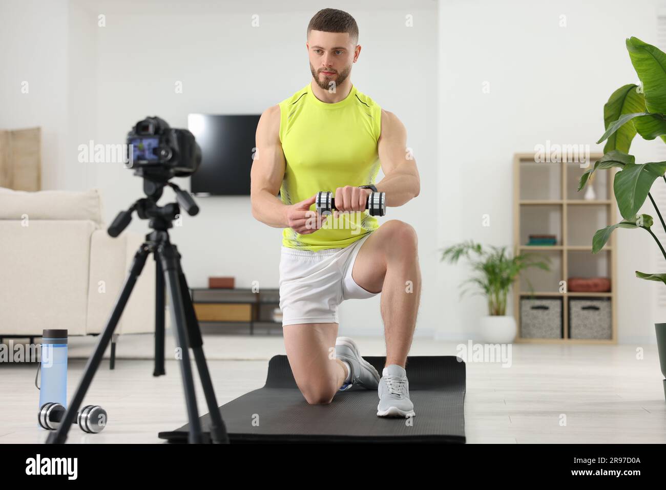 Trainer with dumbbell recording workout on camera at home Stock Photo ...