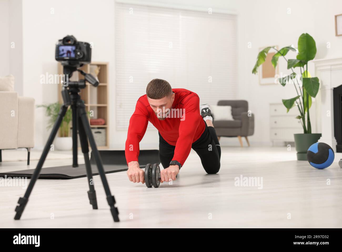 Trainer with ab wheel recording workout on camera at home Stock Photo ...