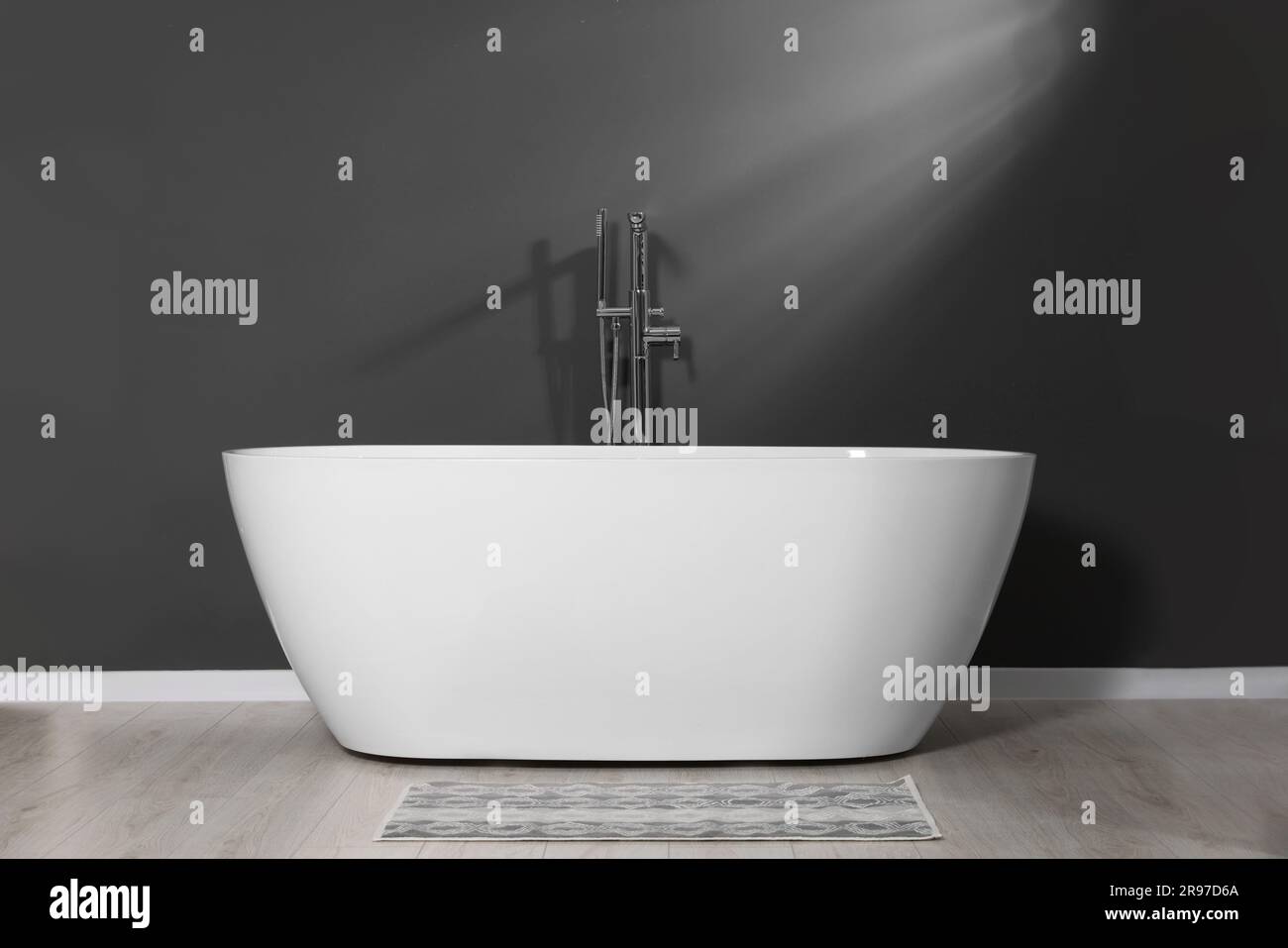 Stylish ceramic tub near grey wall in bathroom Stock Photo - Alamy
