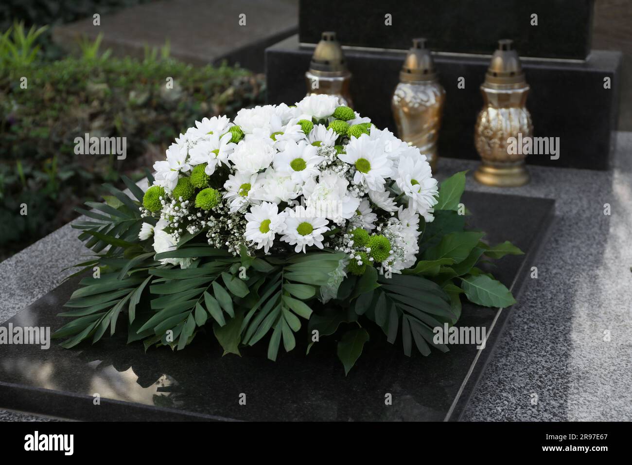 Funeral wreath of flowers and grave lanterns on granite tombstone in cemetery Stock Photo - Alamy